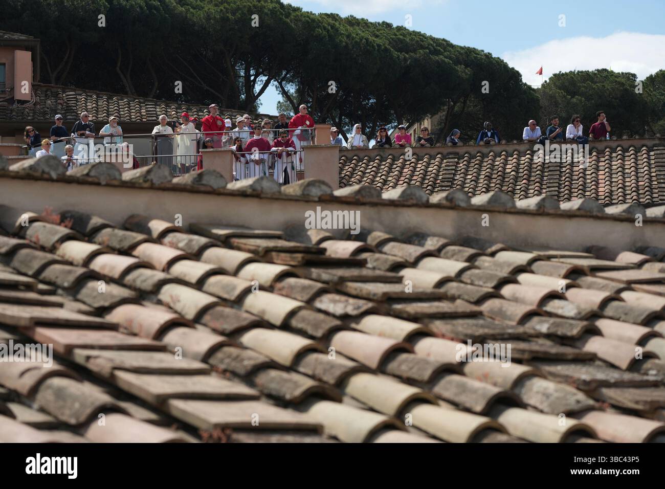 People on a roof follow Pope Leo XIV celebrating the inaugural Mass of ...