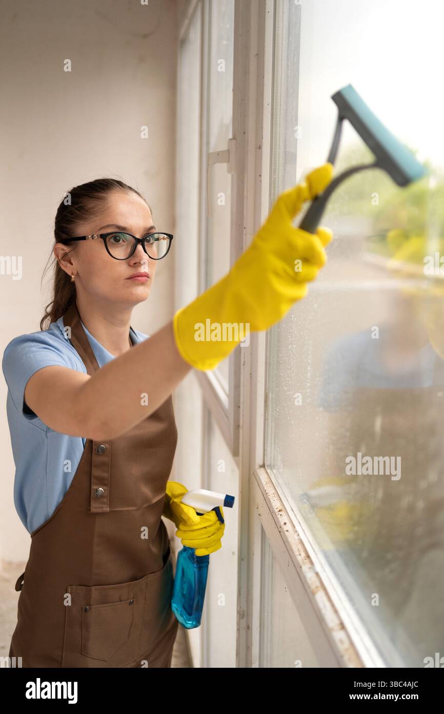 Female cleaner cleaning windows with a squeegee mop. Copy space Stock ...