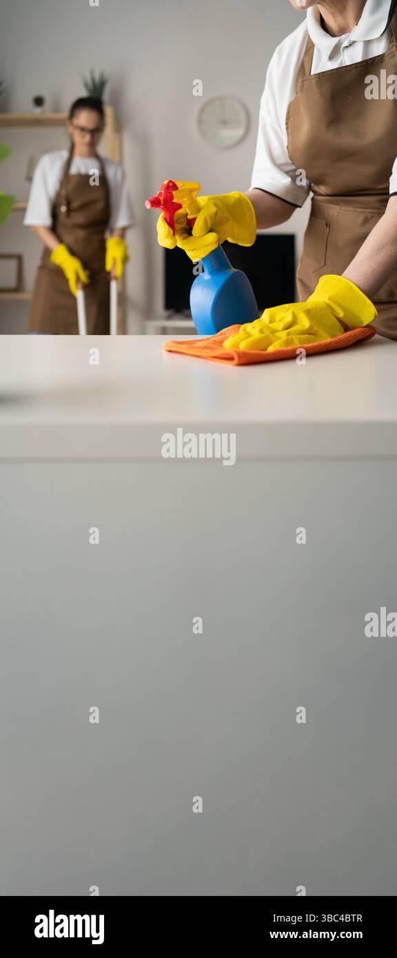 Group of women janitors sweeping floor and spraying tabletop with ...
