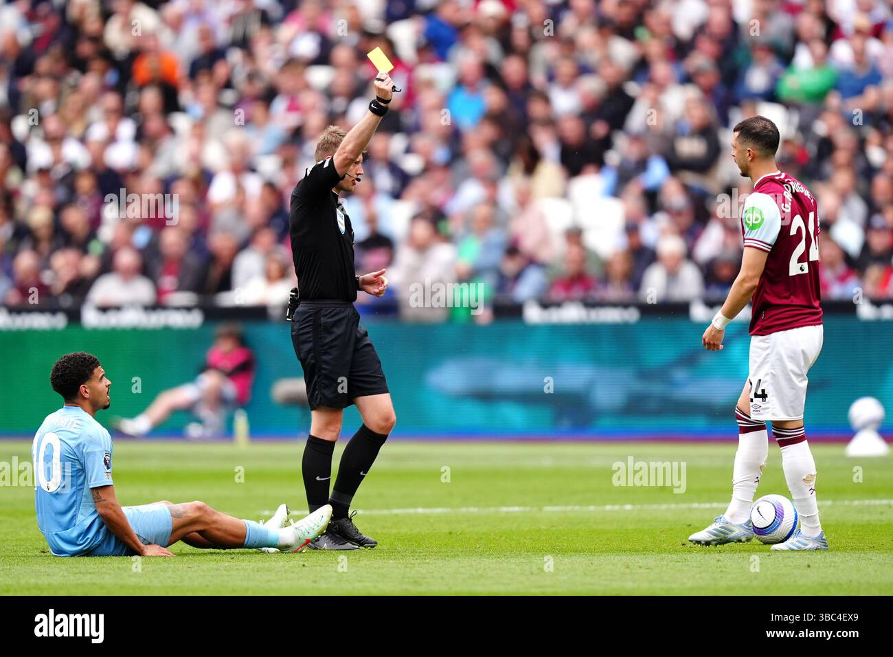 Referee Sam Barrott shows a yellow card to West Ham United's Guido ...