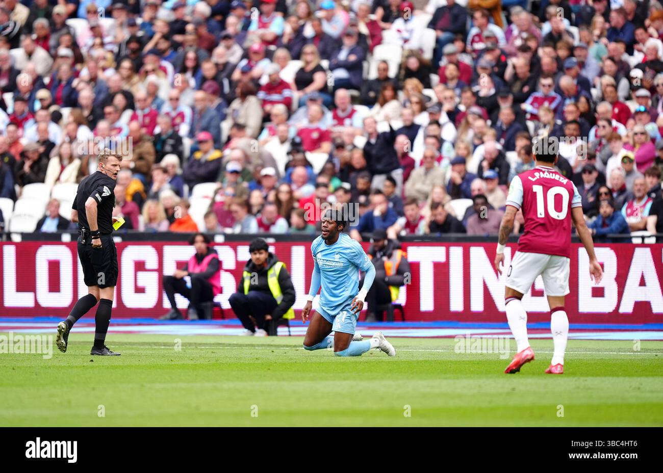Referee Sam Barrott shows a yellow card to West Ham United's Lucas ...
