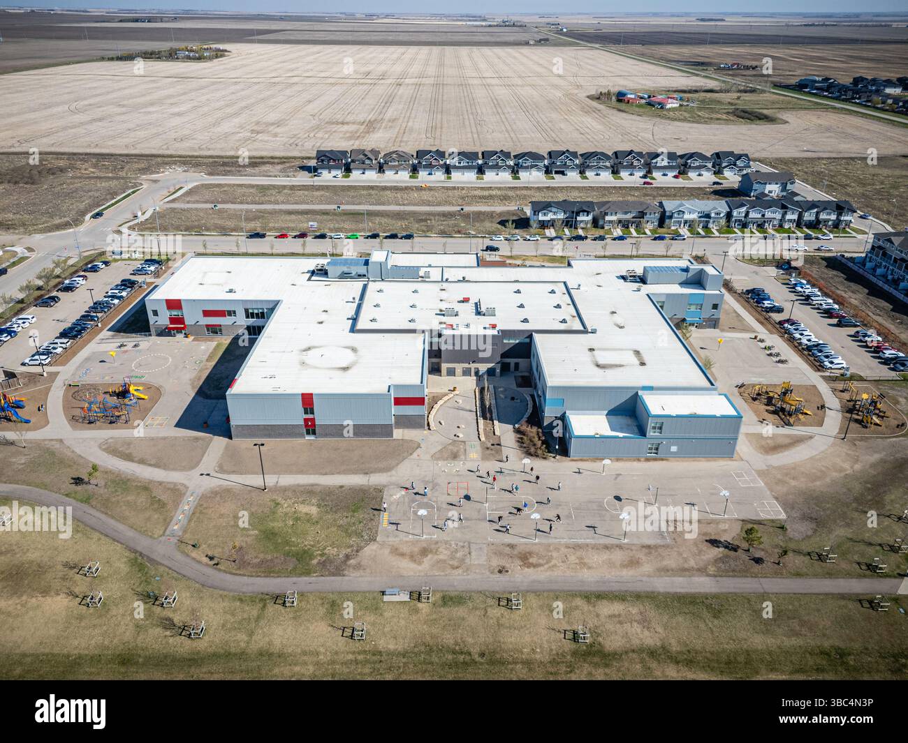 Large school building with a lot of parking lots and a playground. The ...