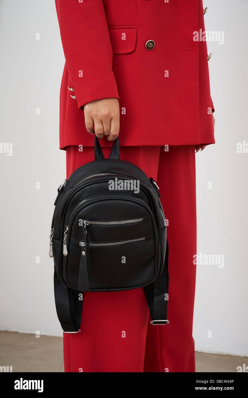 Stylish blonde woman poses with a trendy black backpack in a fashion ...