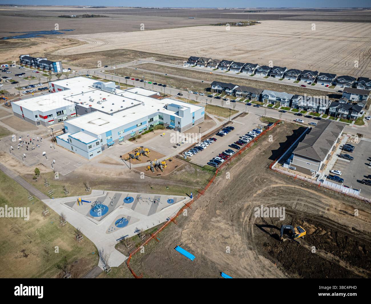 Large school building with a playground and a parking lot. The parking ...