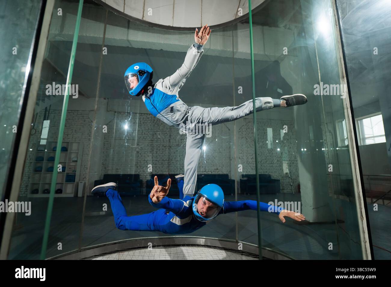 A male instructor teaches a woman how to fly in a wind tunnel. Free ...