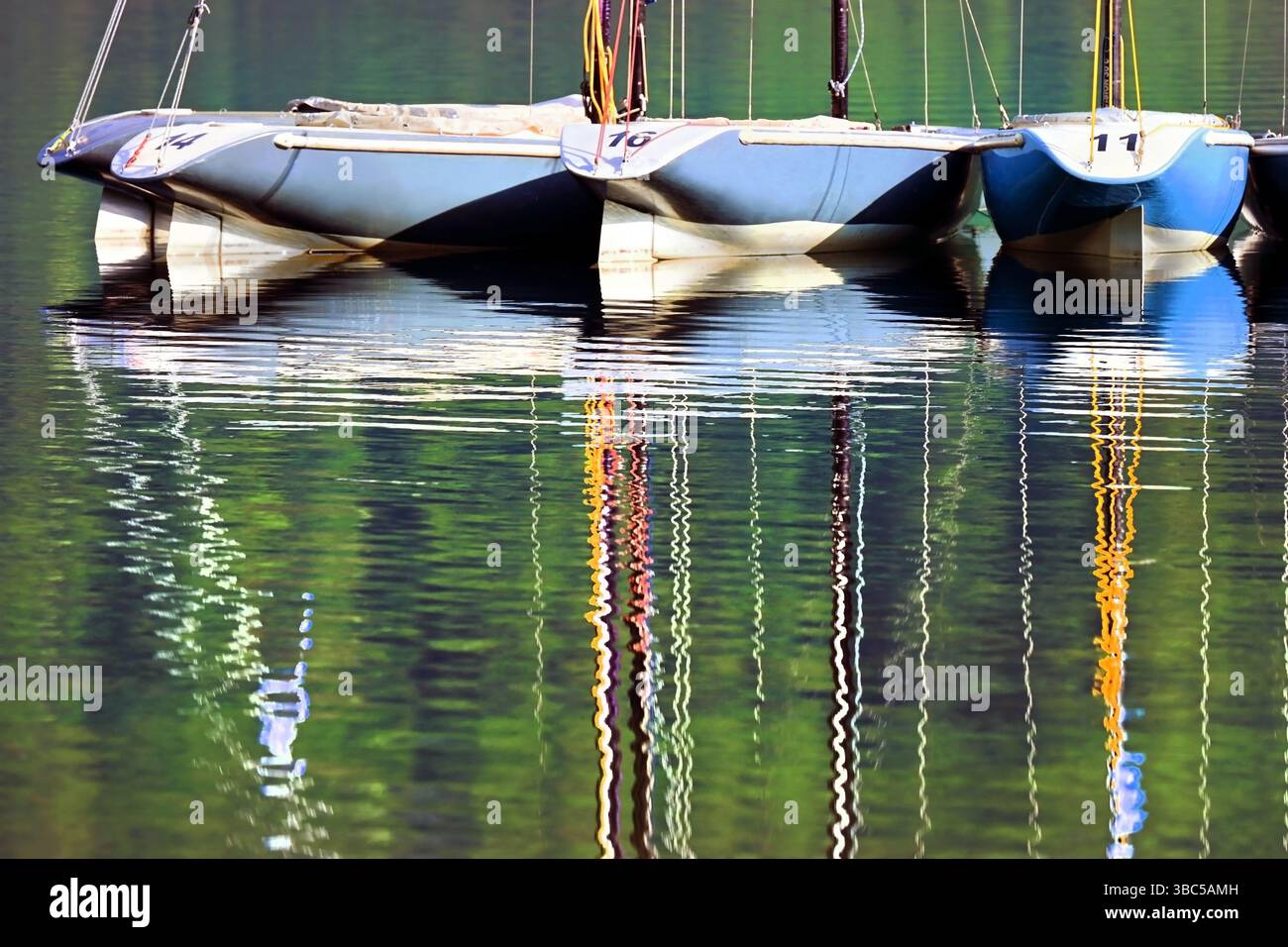 Small sailing boats with reflections in water moored on Lake Bohinj ...