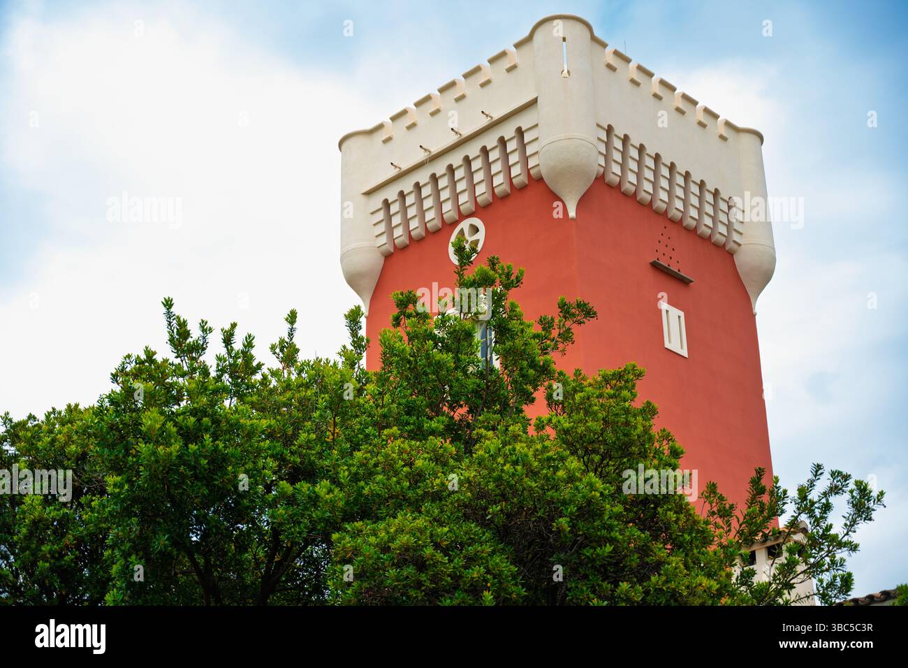 Chateau de Cremat red tower building near a green tree over blue sky ...