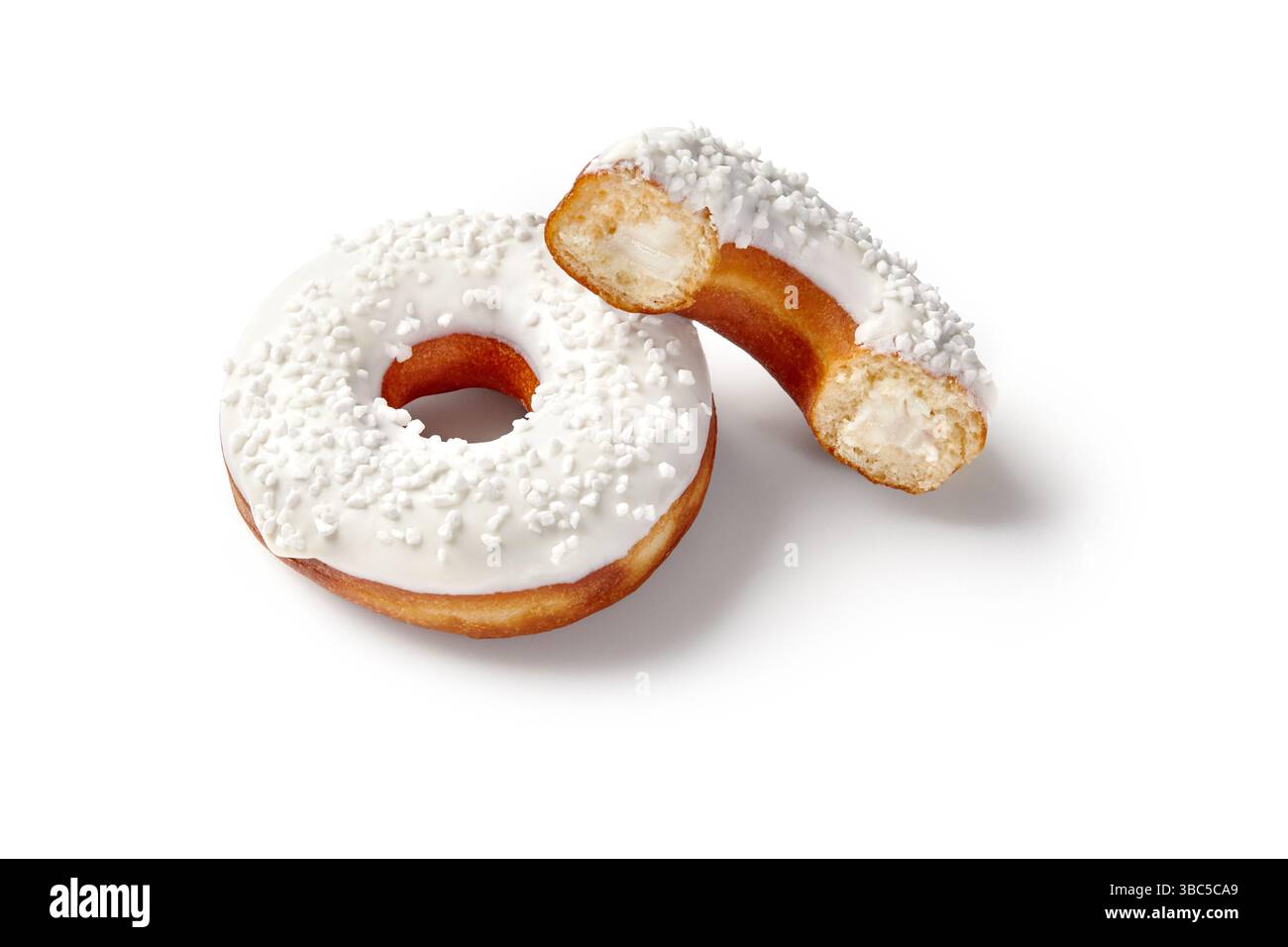 Two delicious donuts with white icing and sprinkles, one split open ...