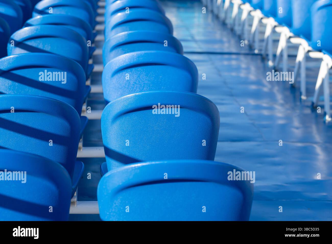 An arrangement of bright blue stadium seats viewed closeup, showcasing ...