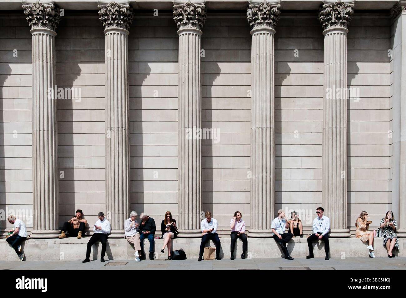 People enjoying London spring sunshine sit at base of columns of the ...