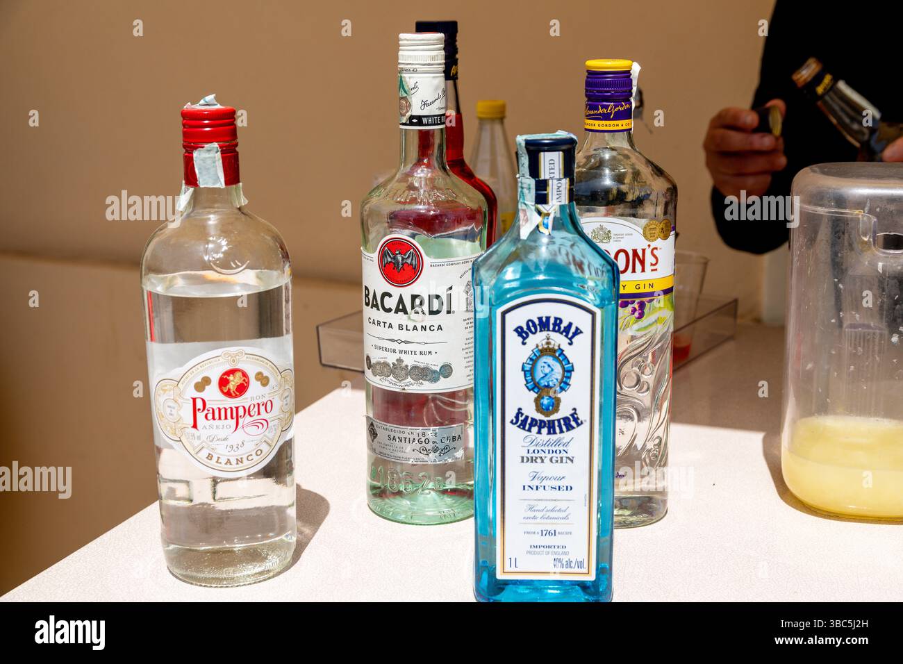 Liquor bottles and juice pitcher on bar counter Stock Photo - Alamy
