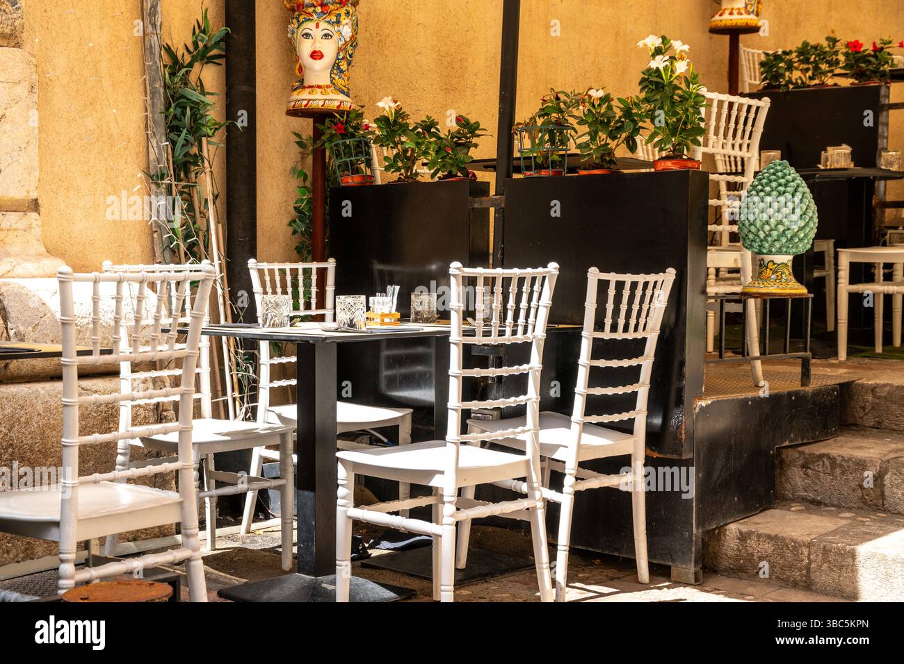 Outdoor cafe table with chairs and Sicilian decor Stock Photo - Alamy
