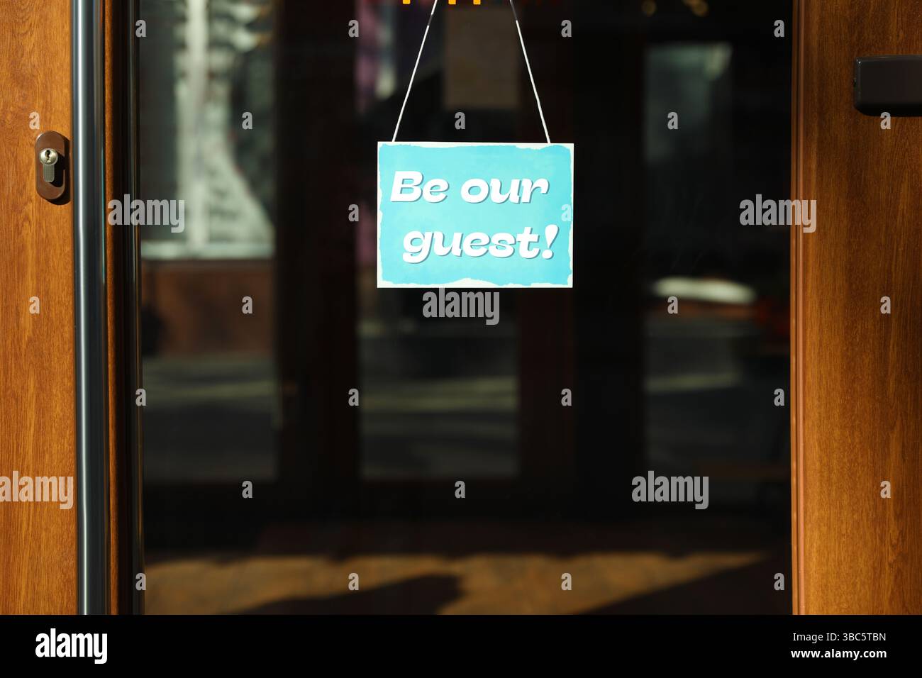 Be Our Guest sign hanging on glass door outdoors Stock Photo - Alamy