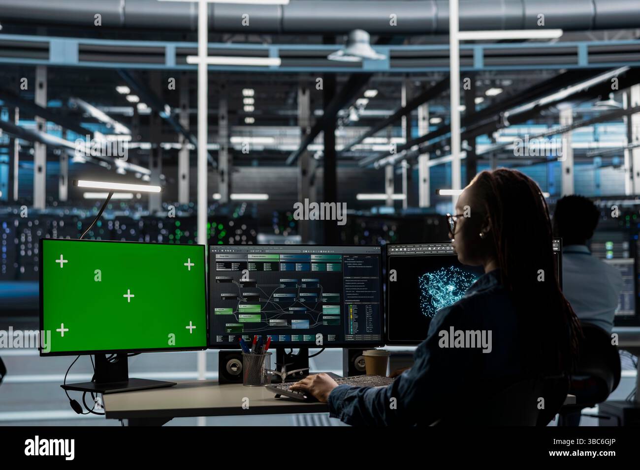 Admin working on green screen desktop PC in data center housing storage infrastructure. IT ...