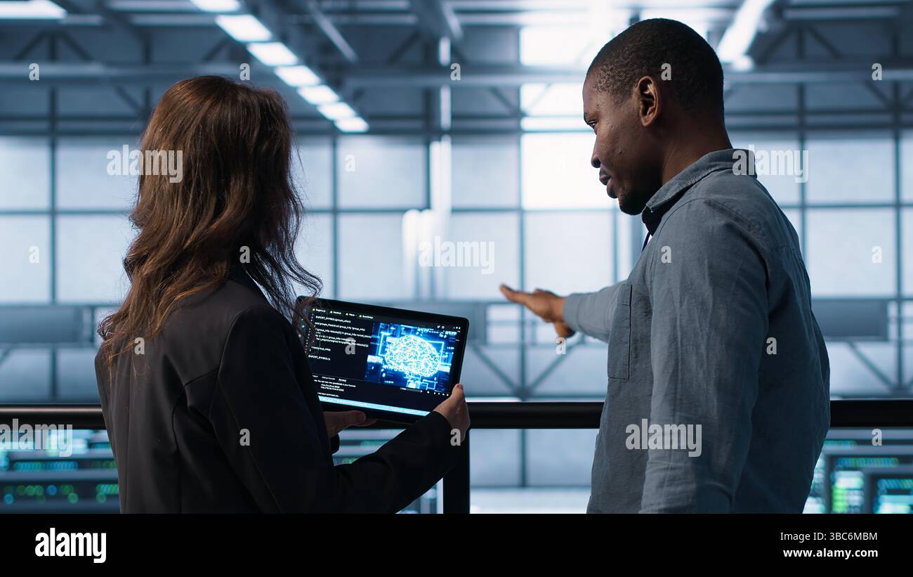 Data center technicians deploying AI driven management tools using tablet. Server farm coworkers ...