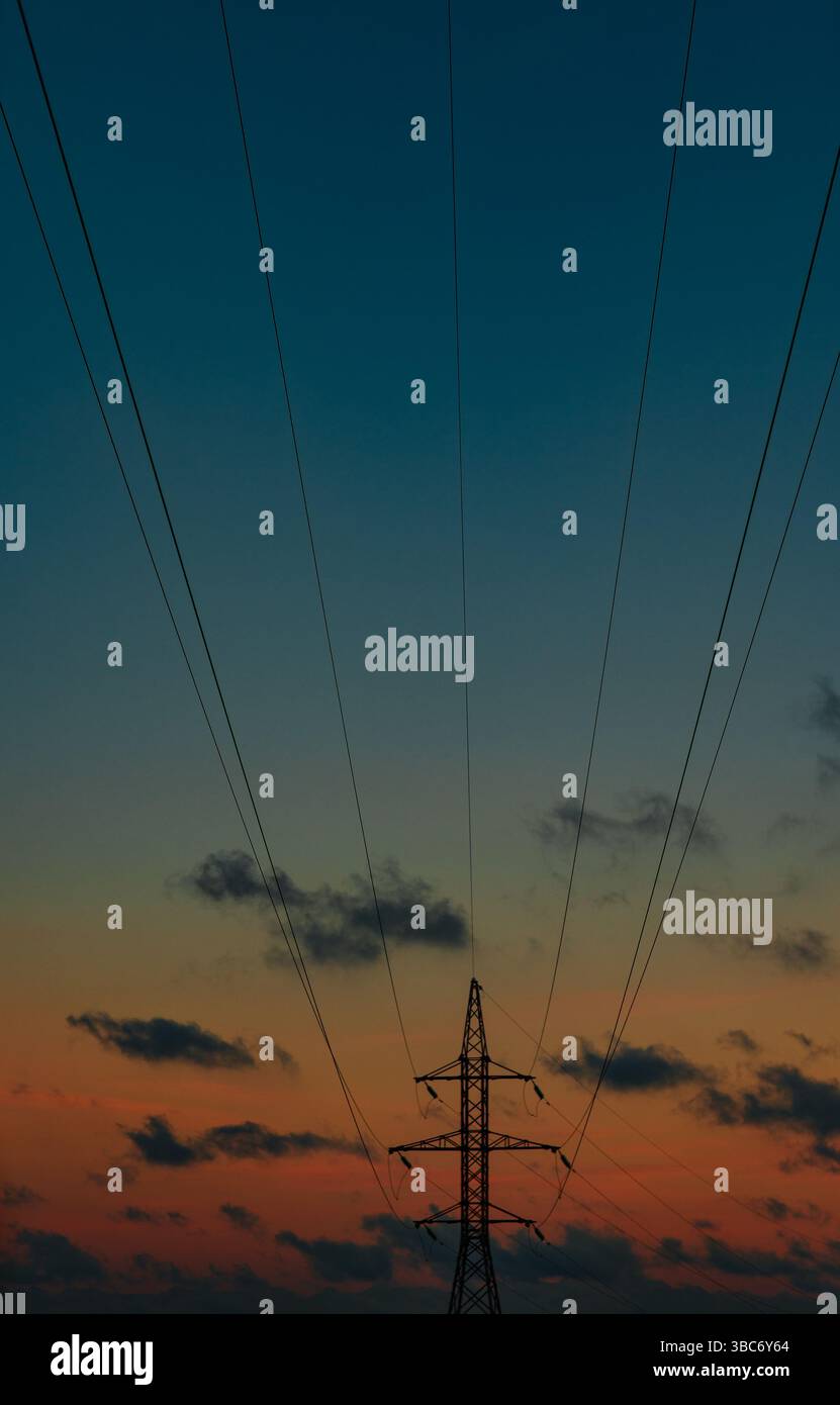 Electric power line at dark sunset light Stock Photo - Alamy