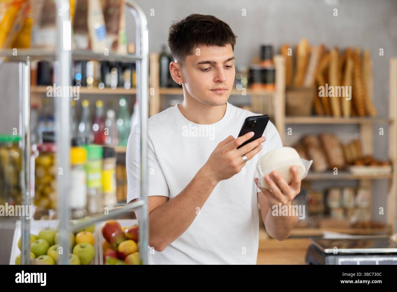 Guy purchaser scanning QR code or barcode of dried meat in supermarket ...