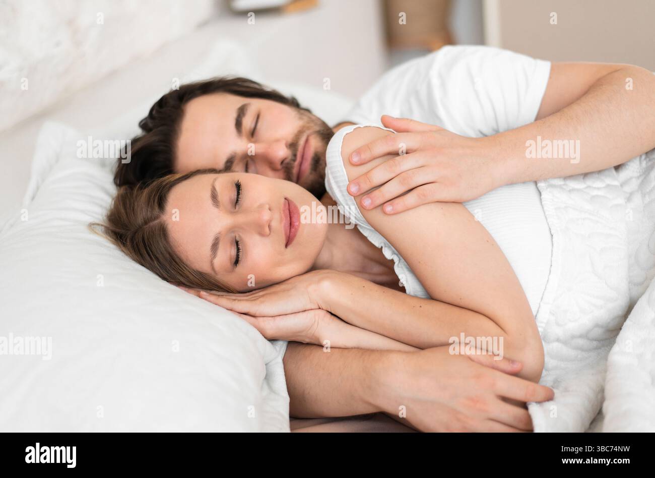 Loving young couple having cozy morning, cuddling together in their sleep on bed Stock Photo - Alamy