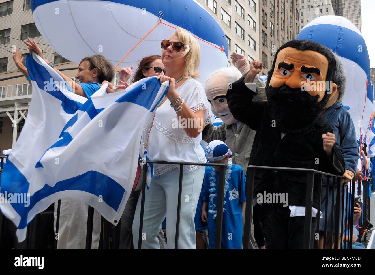Parade participants wave the Israeli flags while standing on a float at ...