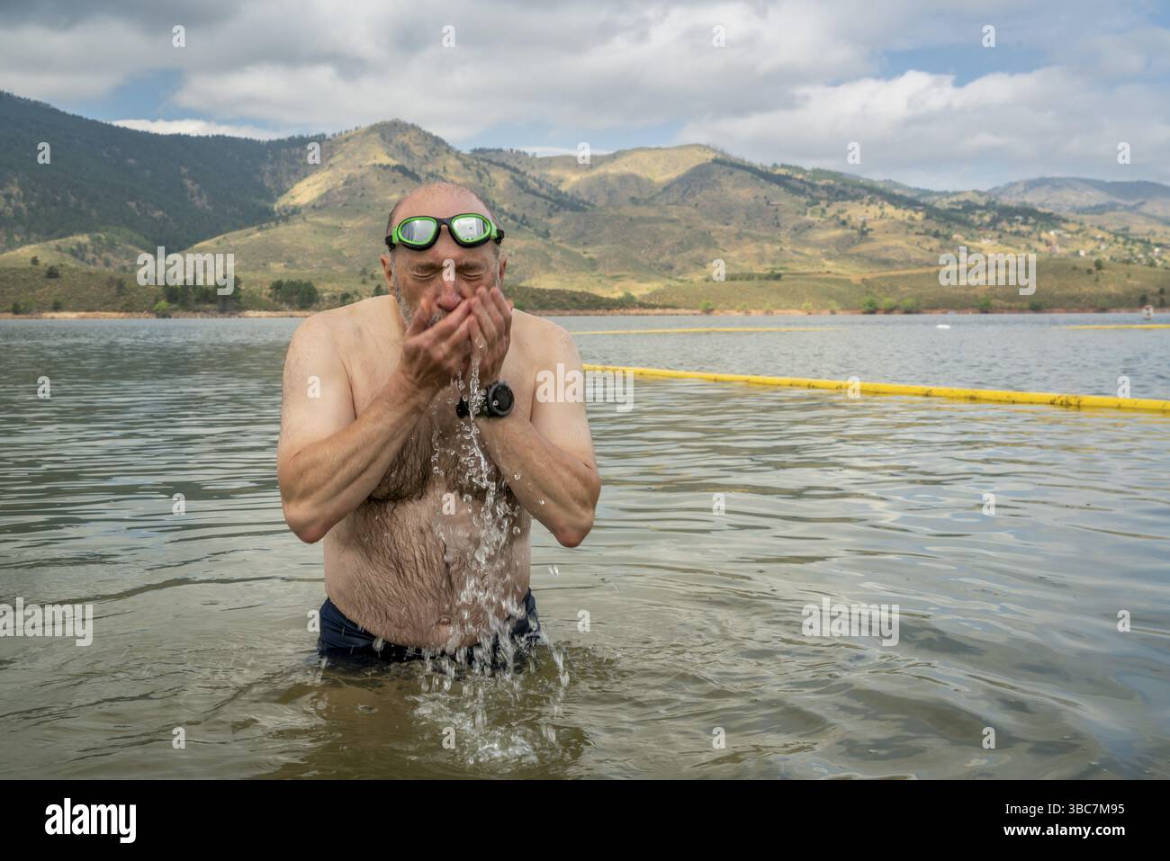 Active senior man is rinsing his face after swimming workout in a ...