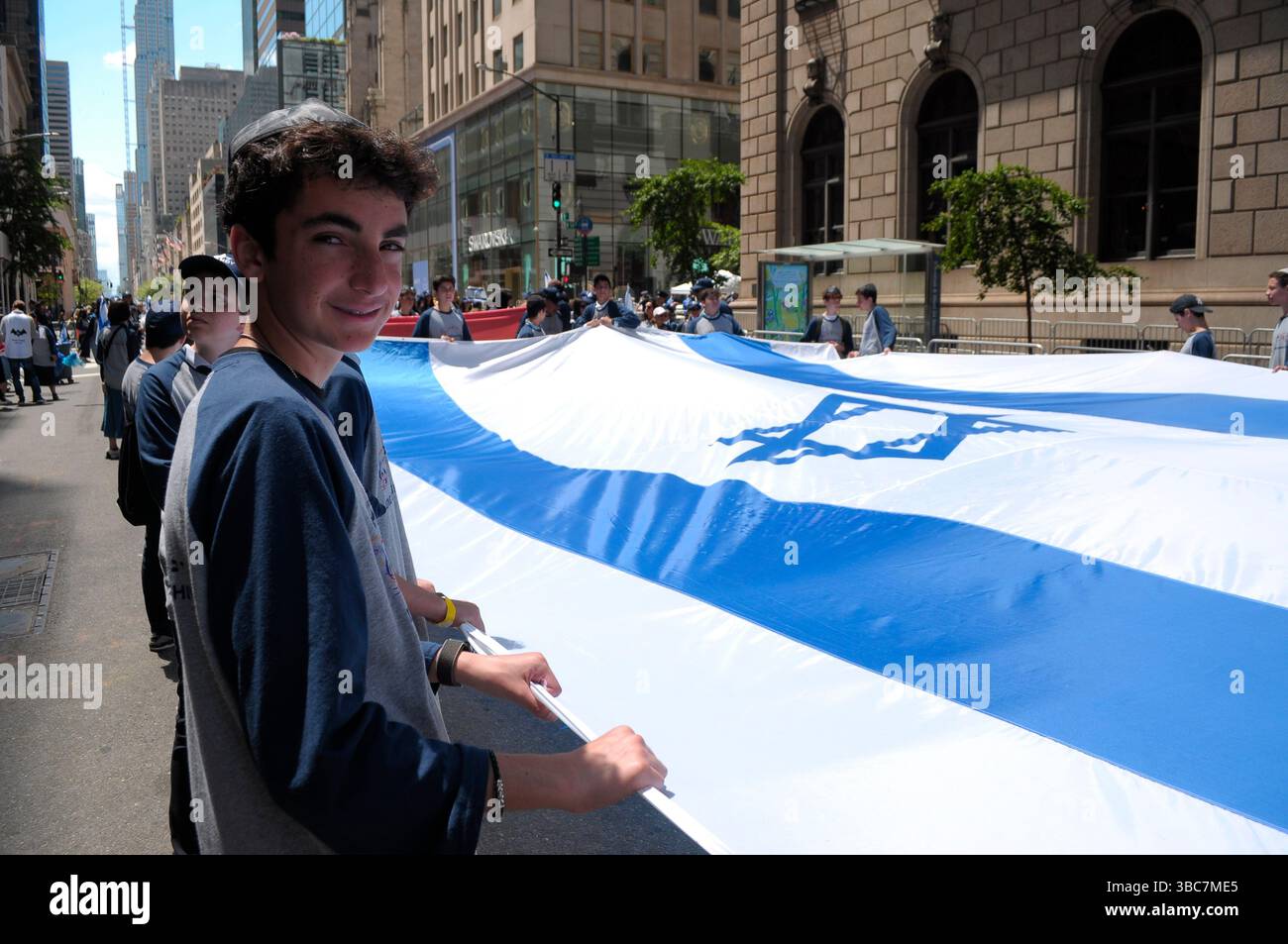 Parade participants hold a large Israeli flag while marching at the ...