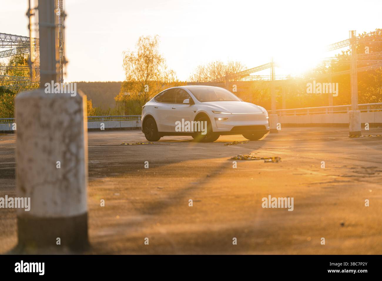 White car at sunset in an urban car park with light columns, Tesla new ...