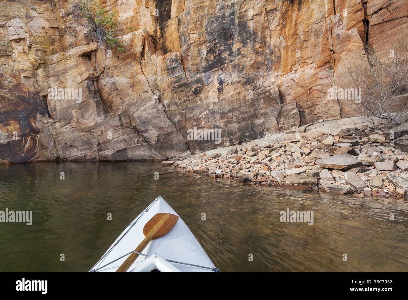 Canoe bow with a paddle on Horsetooth Reservoir with a high sandstone ...