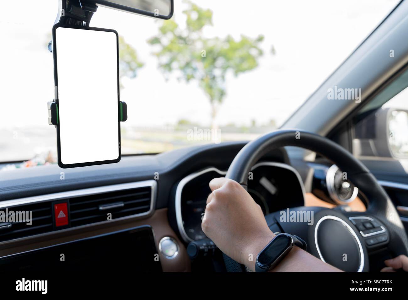 Close-up of driver’s hand on steering wheel and smartphone with blank ...