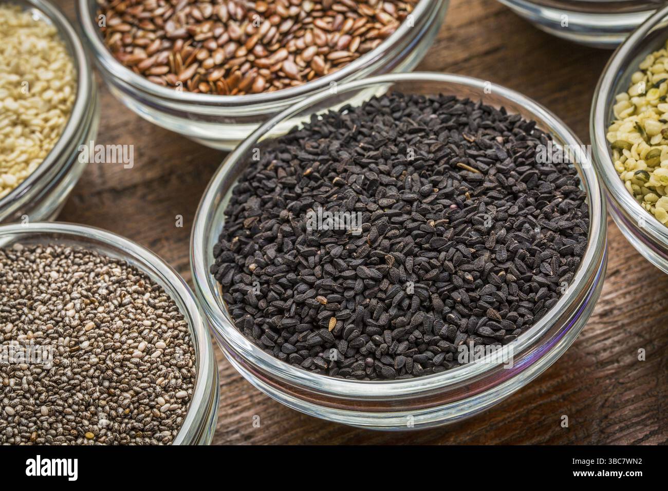 Black cumin seeds (Nigella sativa) in a small bowl against rustic barn ...