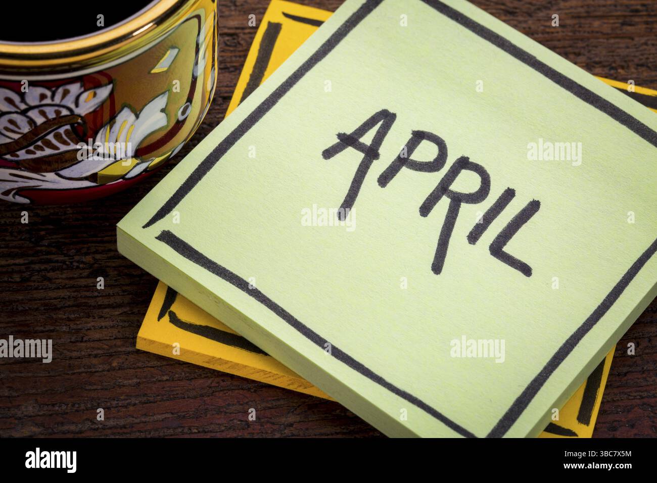 April - handwriting in black ink on a sticky note with a cup of coffee ...
