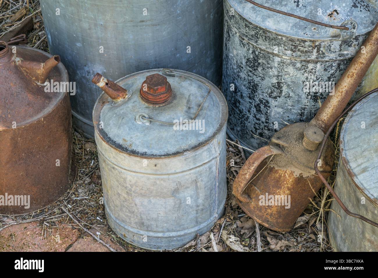 Vintage rusty oil cans of different sizes neglected in a farm workshop ...