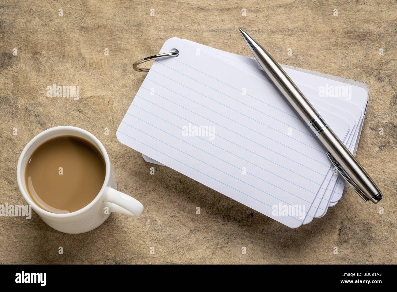 A stack of blank index cards with a cup of coffee and a pen against ...