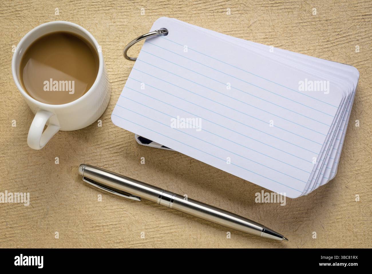 A stack of blank index cards with a cup of coffee and a pen against ...