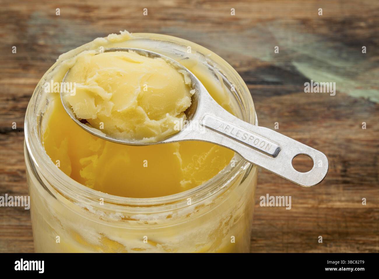 Jar and measuring tablespoon of ghee - clarified butter Stock Photo - Alamy