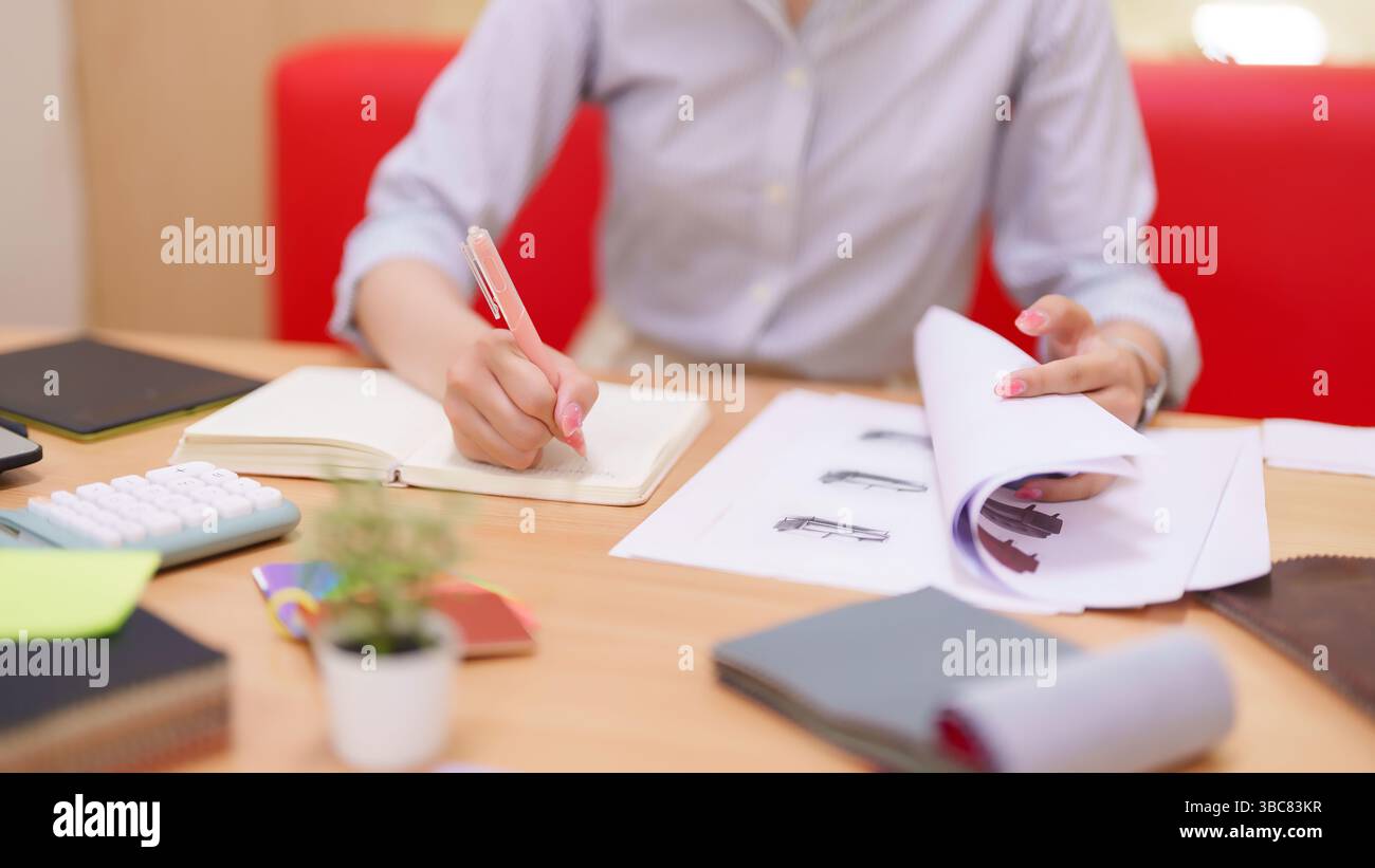 An Asian adult woman interior designer is reviewing blueprints and ...