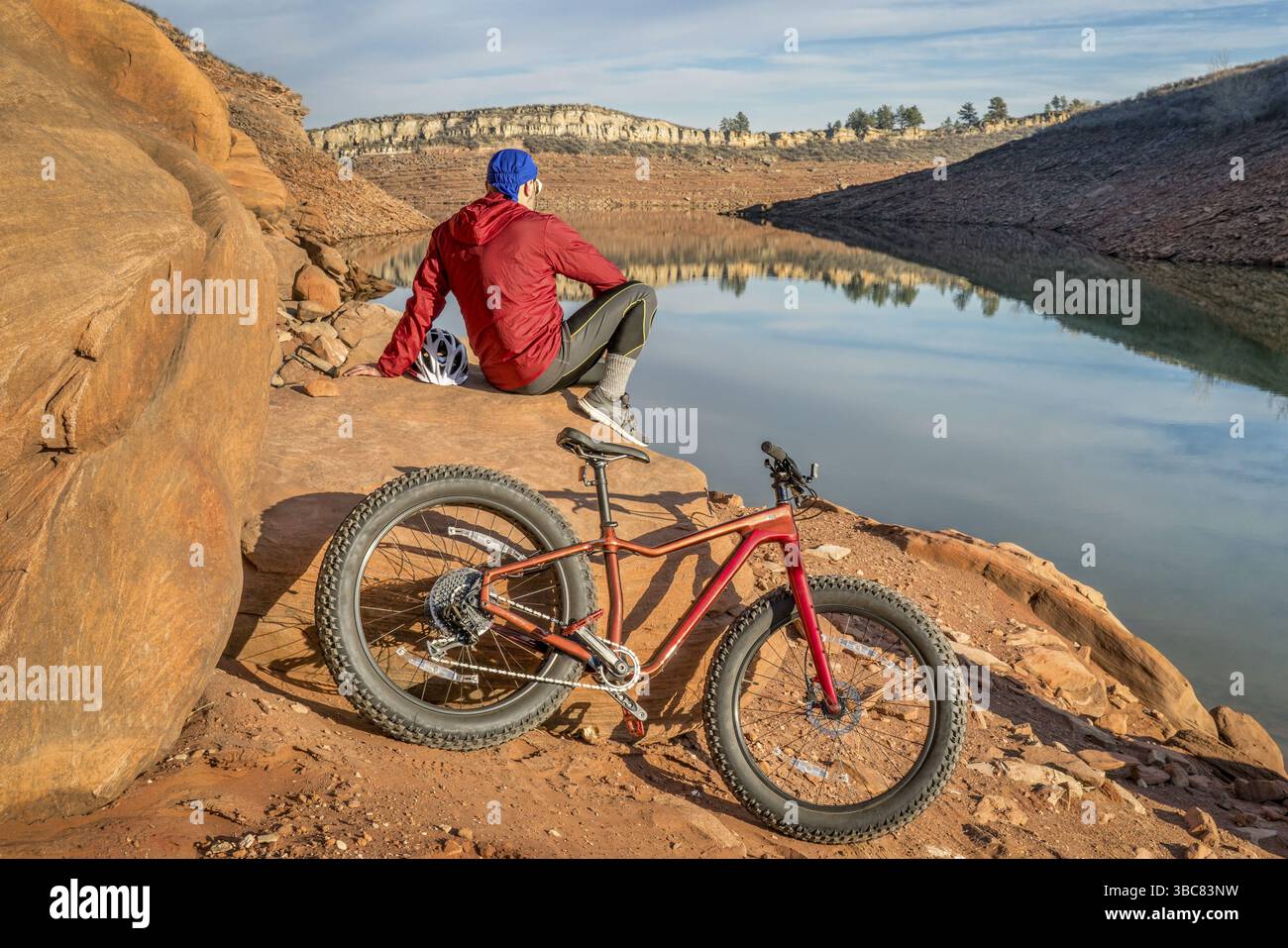 A male biker resting on a shore of Horsetooth Reservoir after rider a ...
