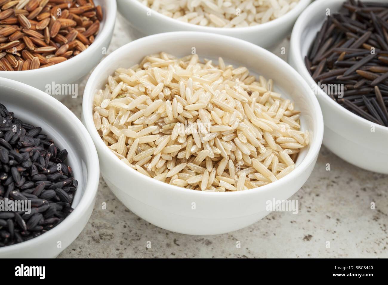 A small bowl of brown basmati rice grain among bowls of other grains ...