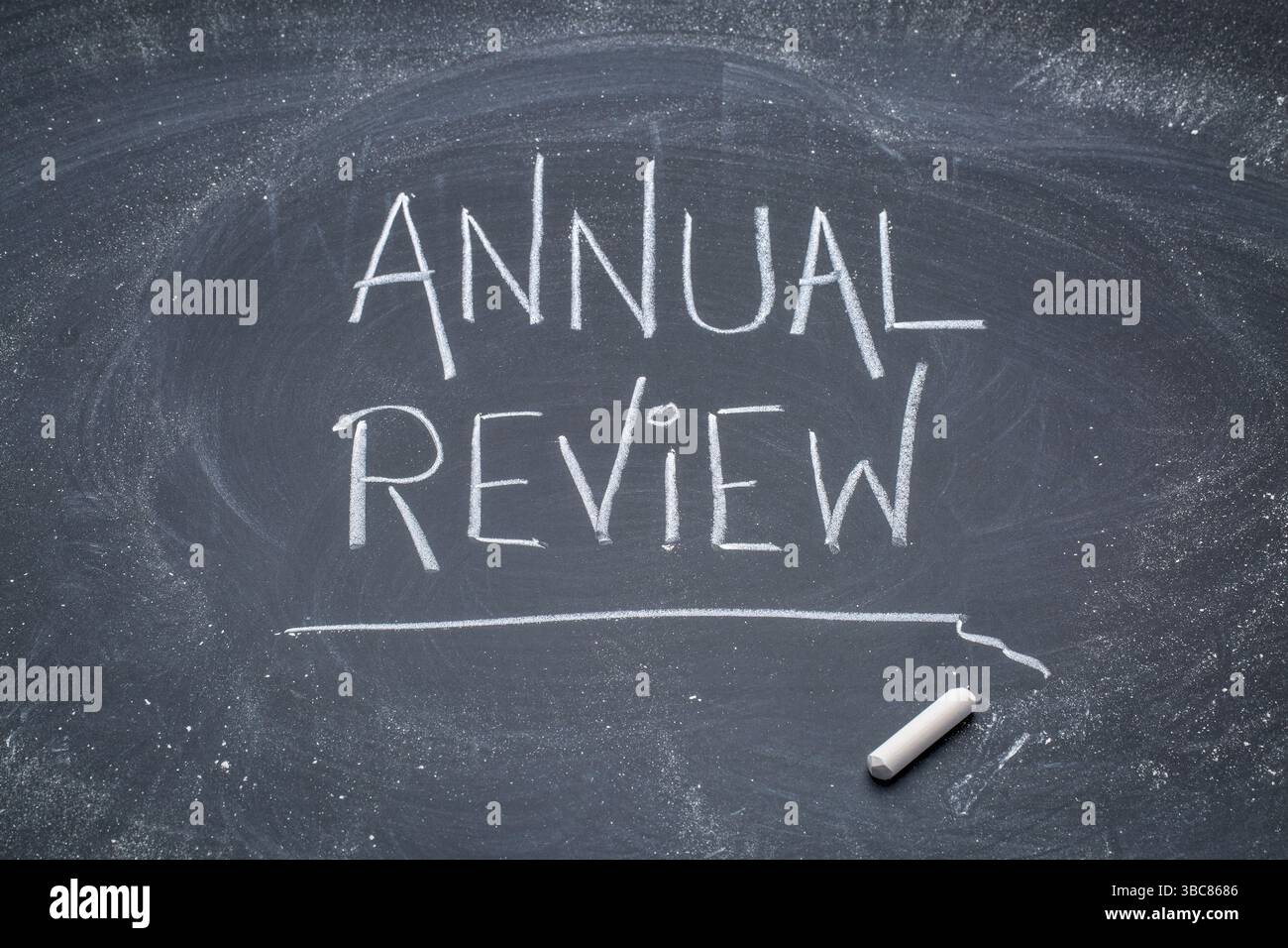 Annual review sign - white chalk messy handwriting on a blackboard ...