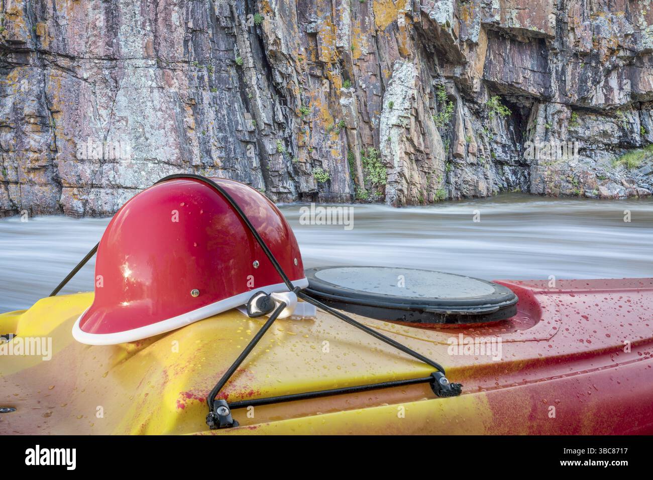 Whitewater kayaking helmet on a kayak deck against river rapid and ...