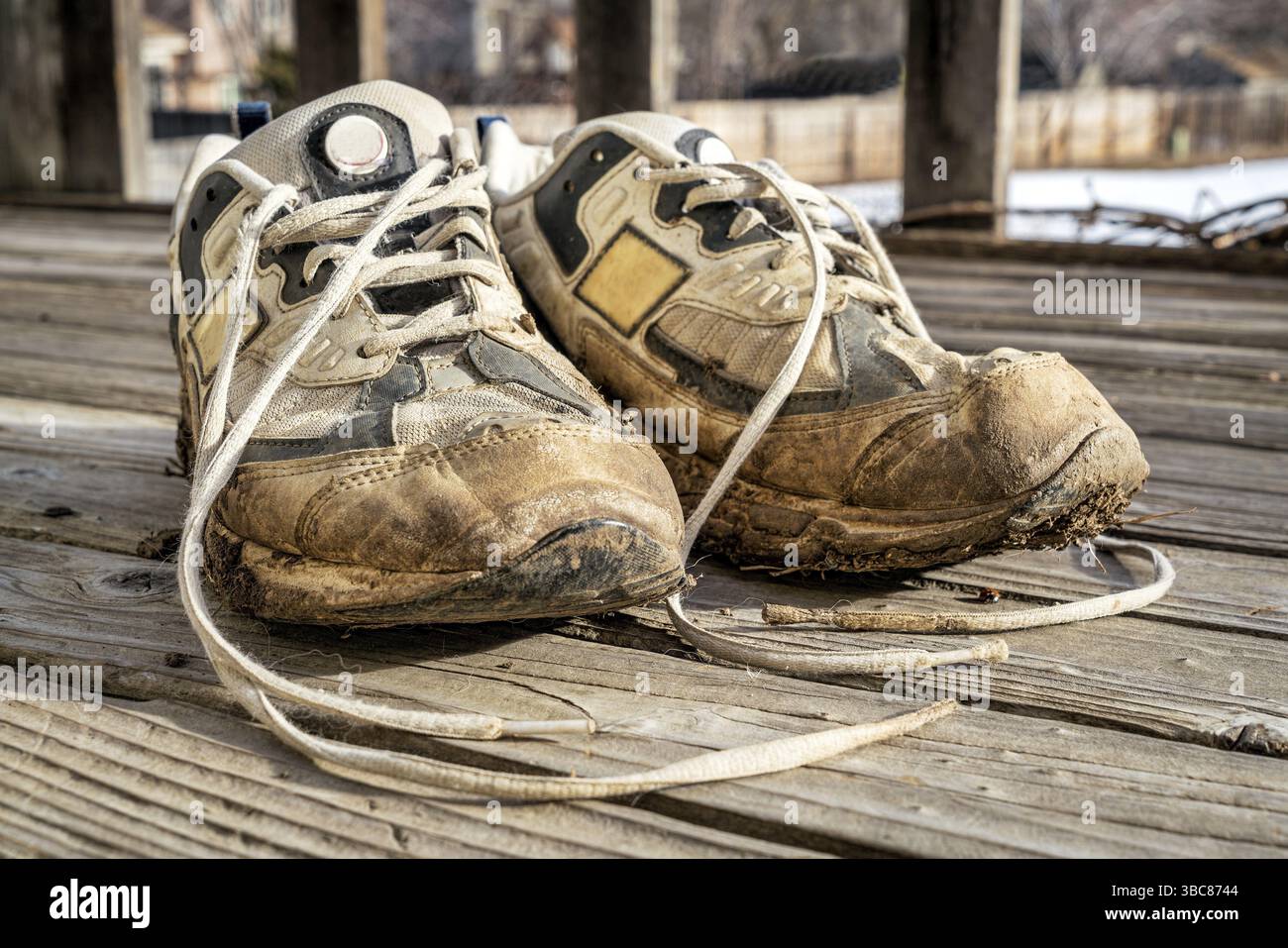 A pair of old muddy running shoes against wooden deck Stock Photo - Alamy