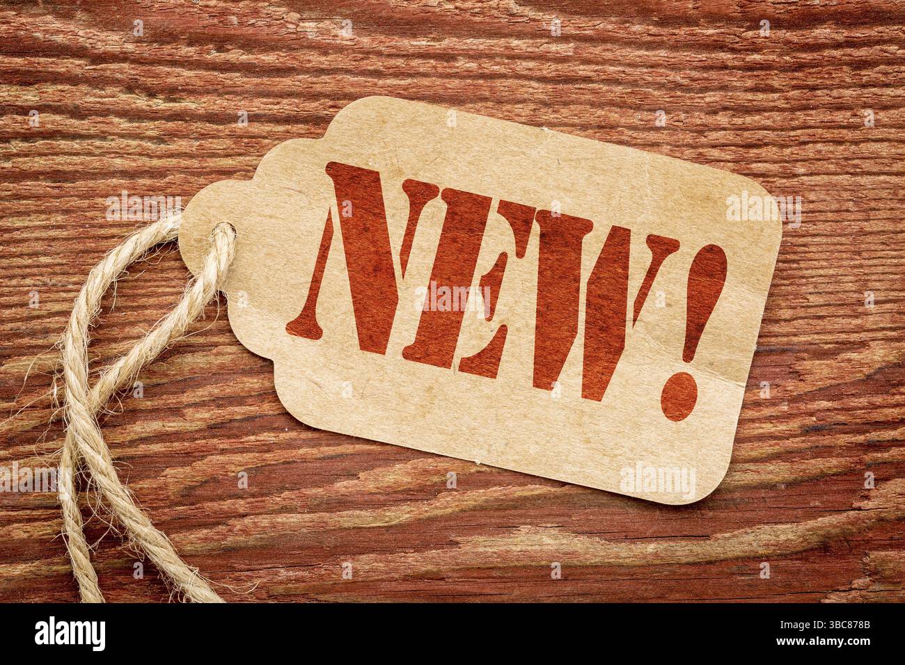 New sign - red stencil text on a paper price tag against grunge wood ...