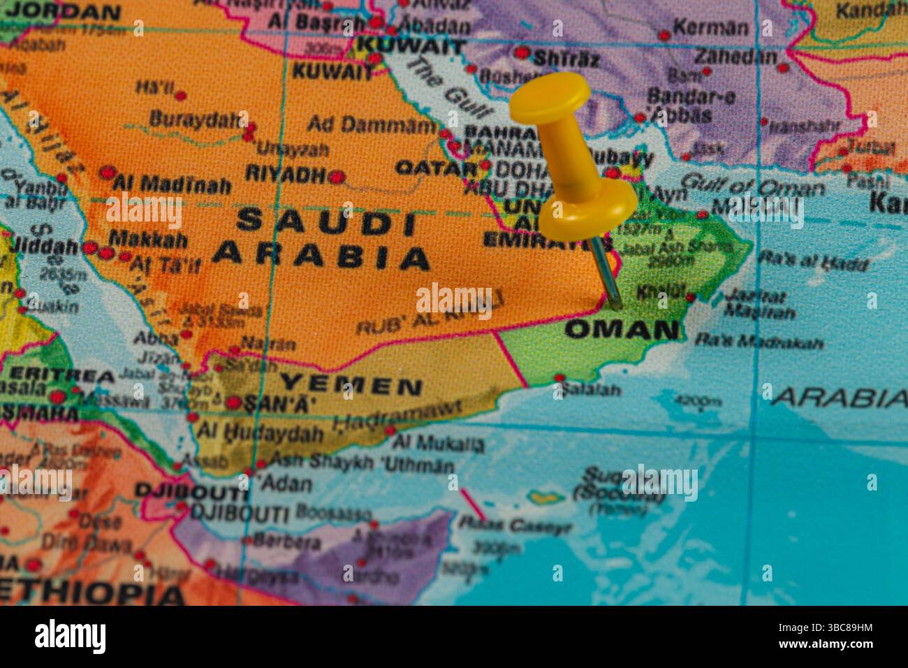 A bright yellow push pin marks the location of Oman on a detailed map ...