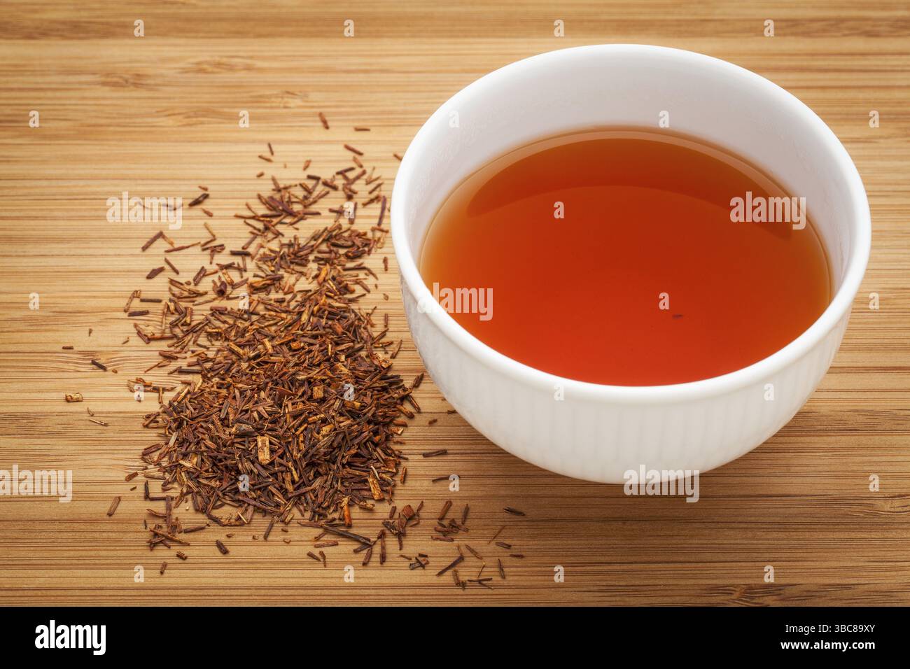 Rooibos red tea - a white cup of a drink and loose leaves on bamboo ...