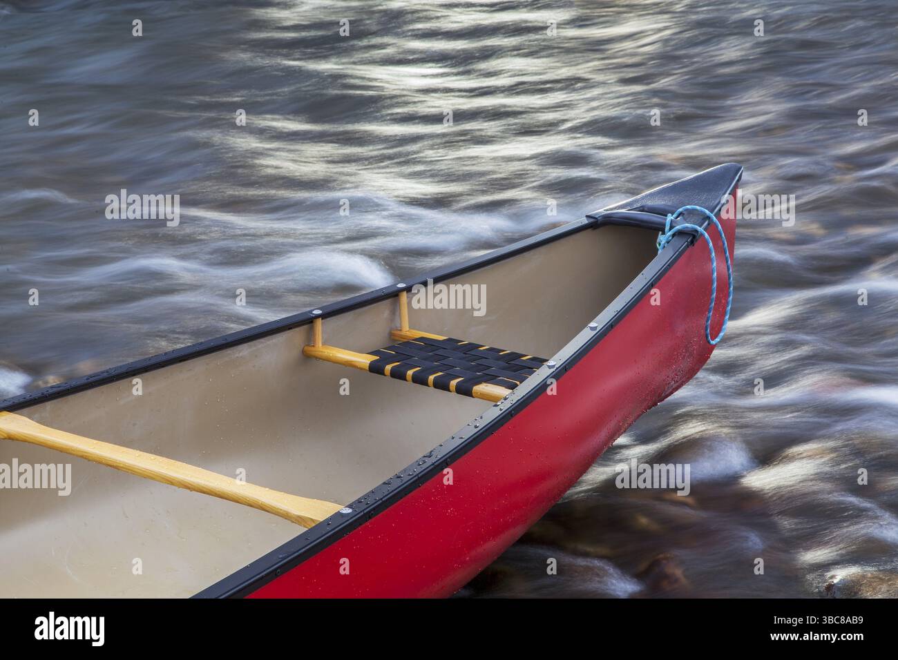 Invitation to paddling - red canoe bow with a rope against river flow ...