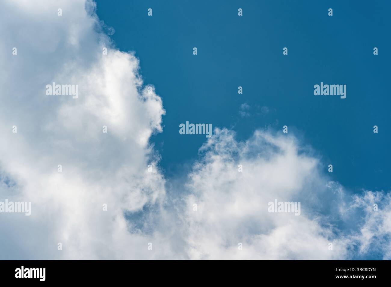 Fluffy white clouds in a bright blue daytime sky Stock Photo - Alamy