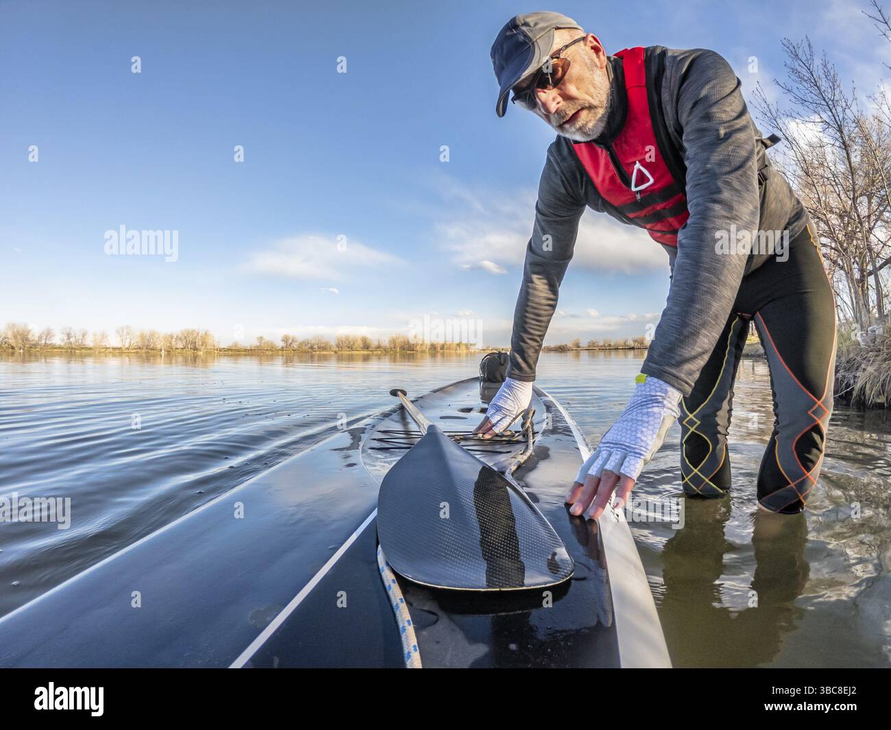 Senior paddler wearing inflatable life jacket and paddling gloves is ...