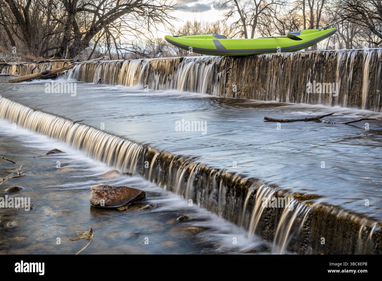 Whitewater inflatable kayak with a paddle on top of river diversion dam ...