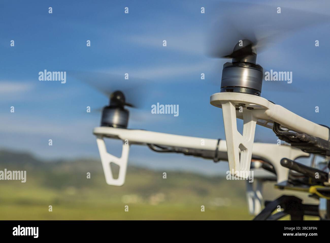 Blurred spinning propellers of a hexacopter drone flying over rolling ...
