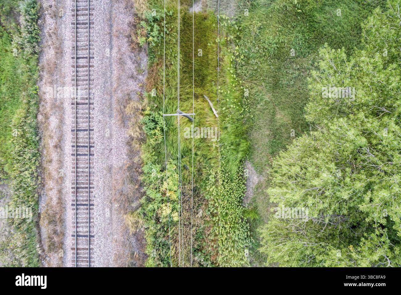 Aerial view of single railroad tracks and electric wires in back ...