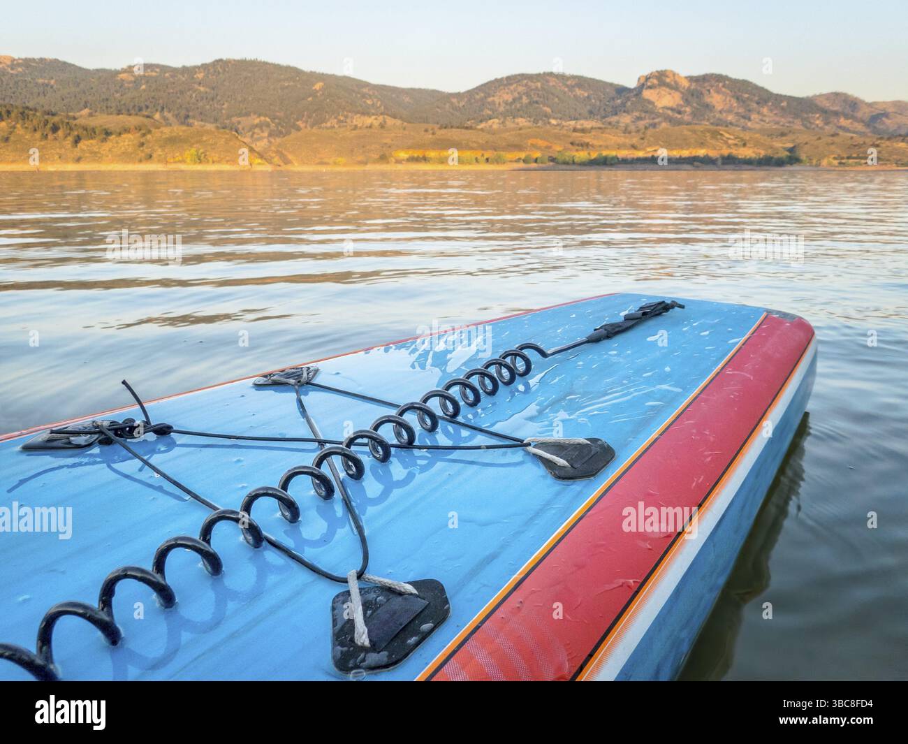 A tail of stand up paddleboard with a leash and bungees on a mountain ...